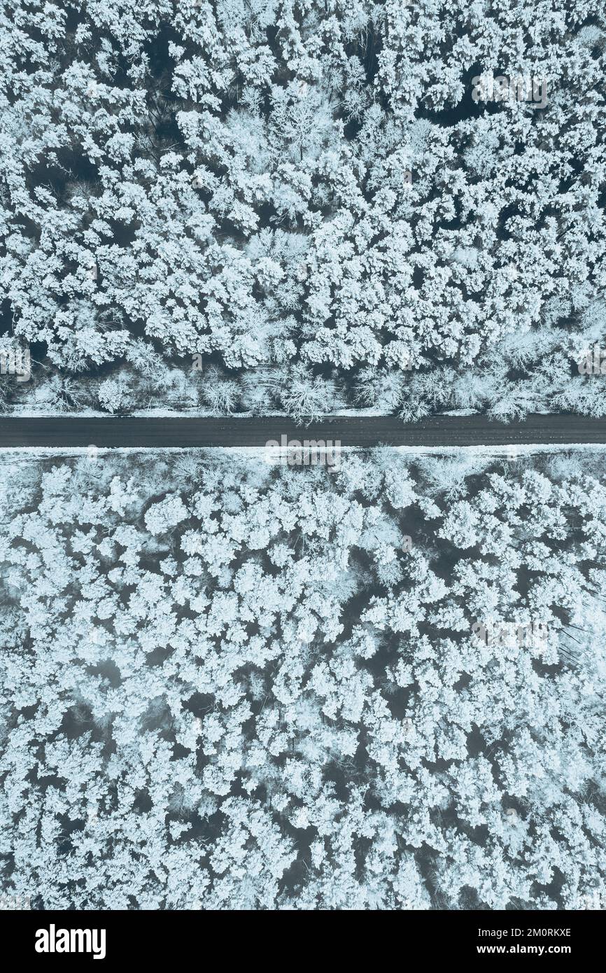 Aerial view of highway road through snow forest landscape in winter ...