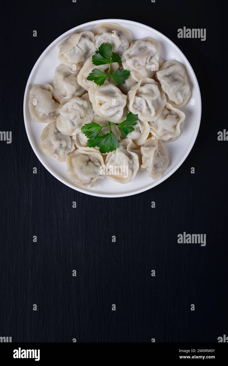 Traditional russian pelmeni, ravioli, dumplings with meat on black ...