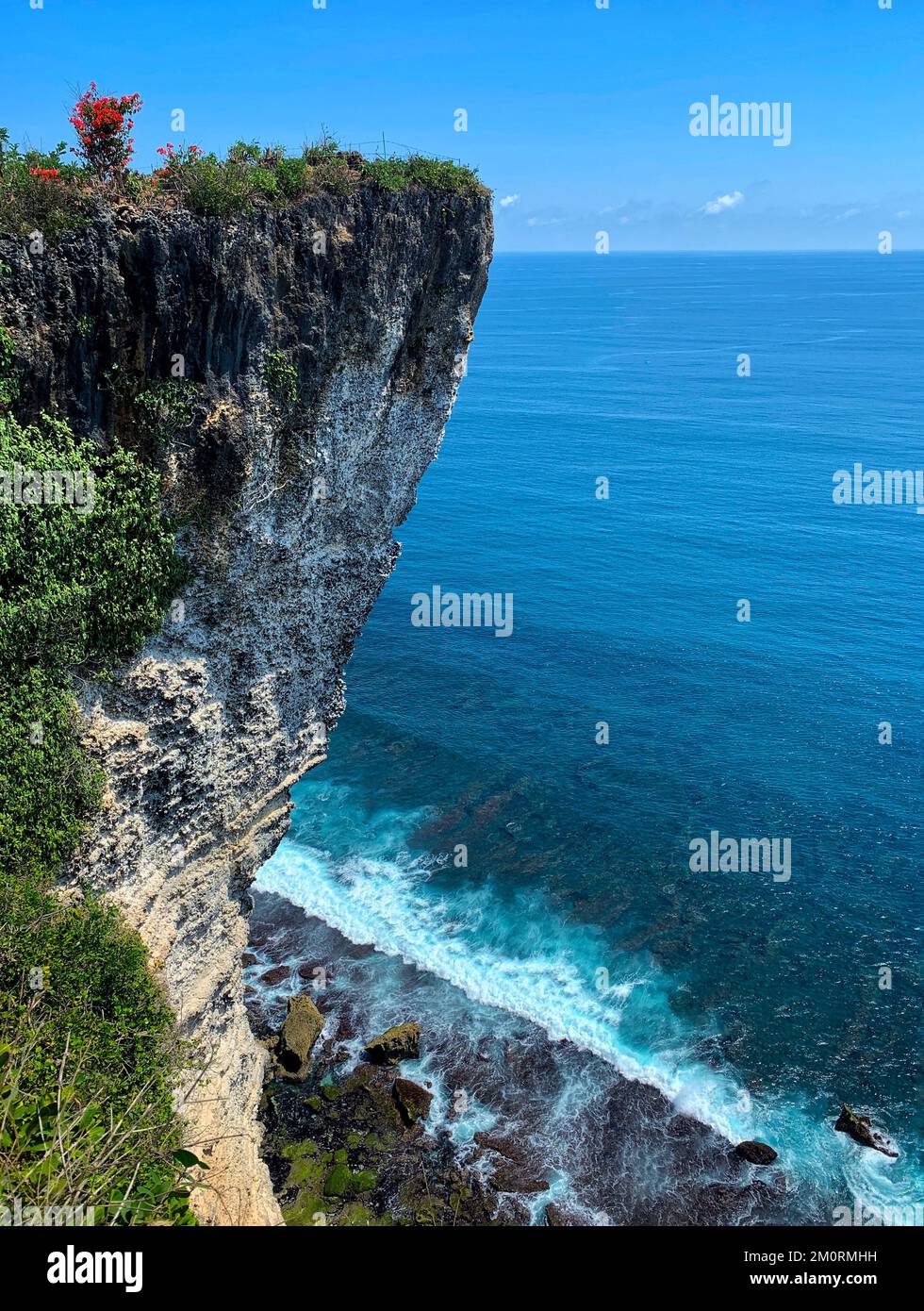 A beautiful shot of a tall cliff by the coastline with clear blue sea ...