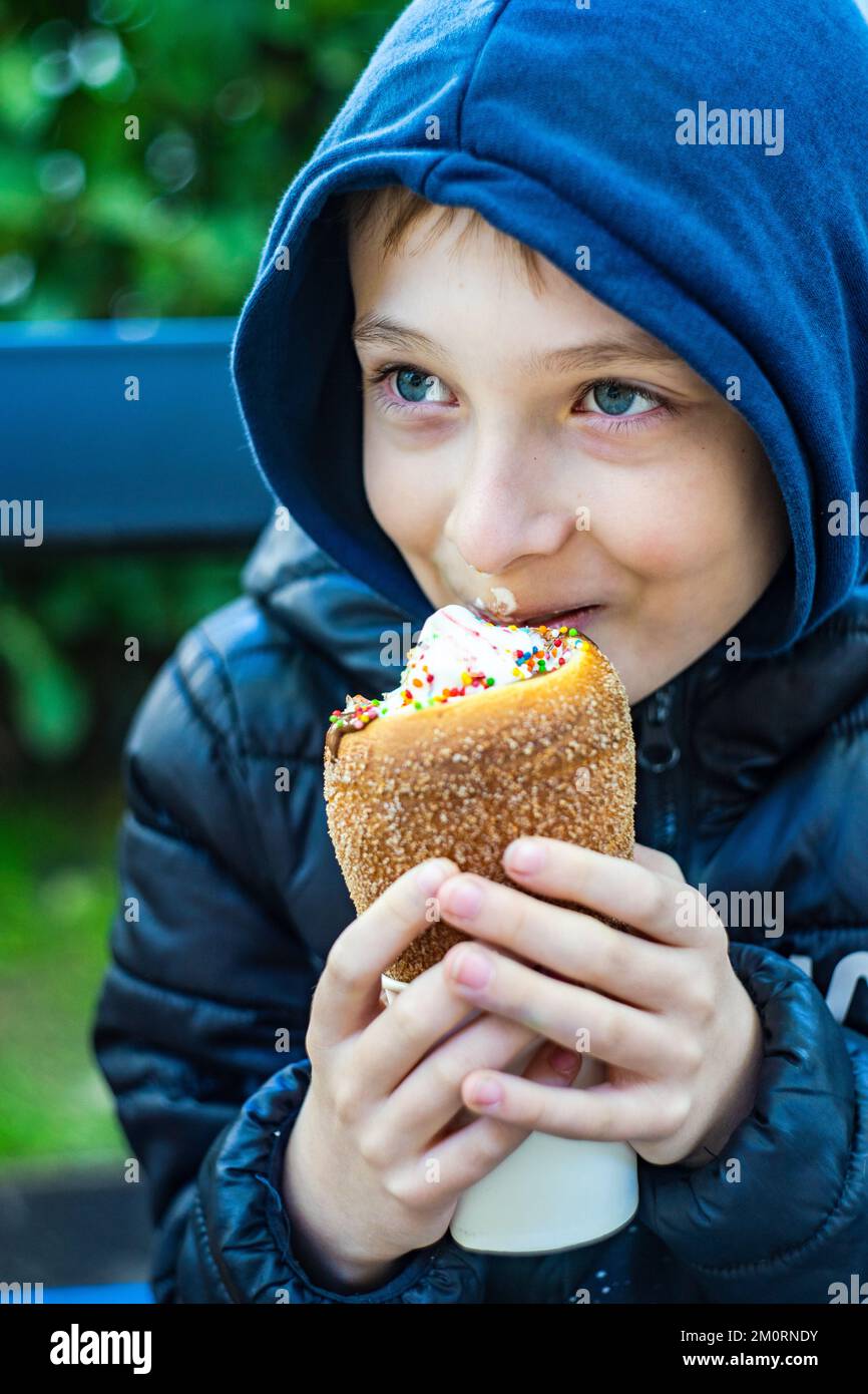 Portrait of a smiling boy eating traditional Hungarian street food ...