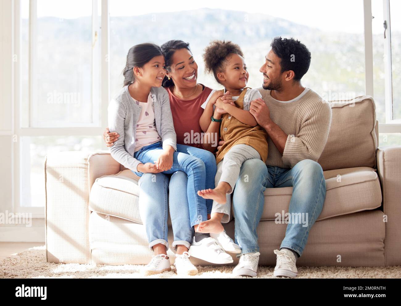 Fullbody shot of a happy, young affectionate family of four sitting on ...