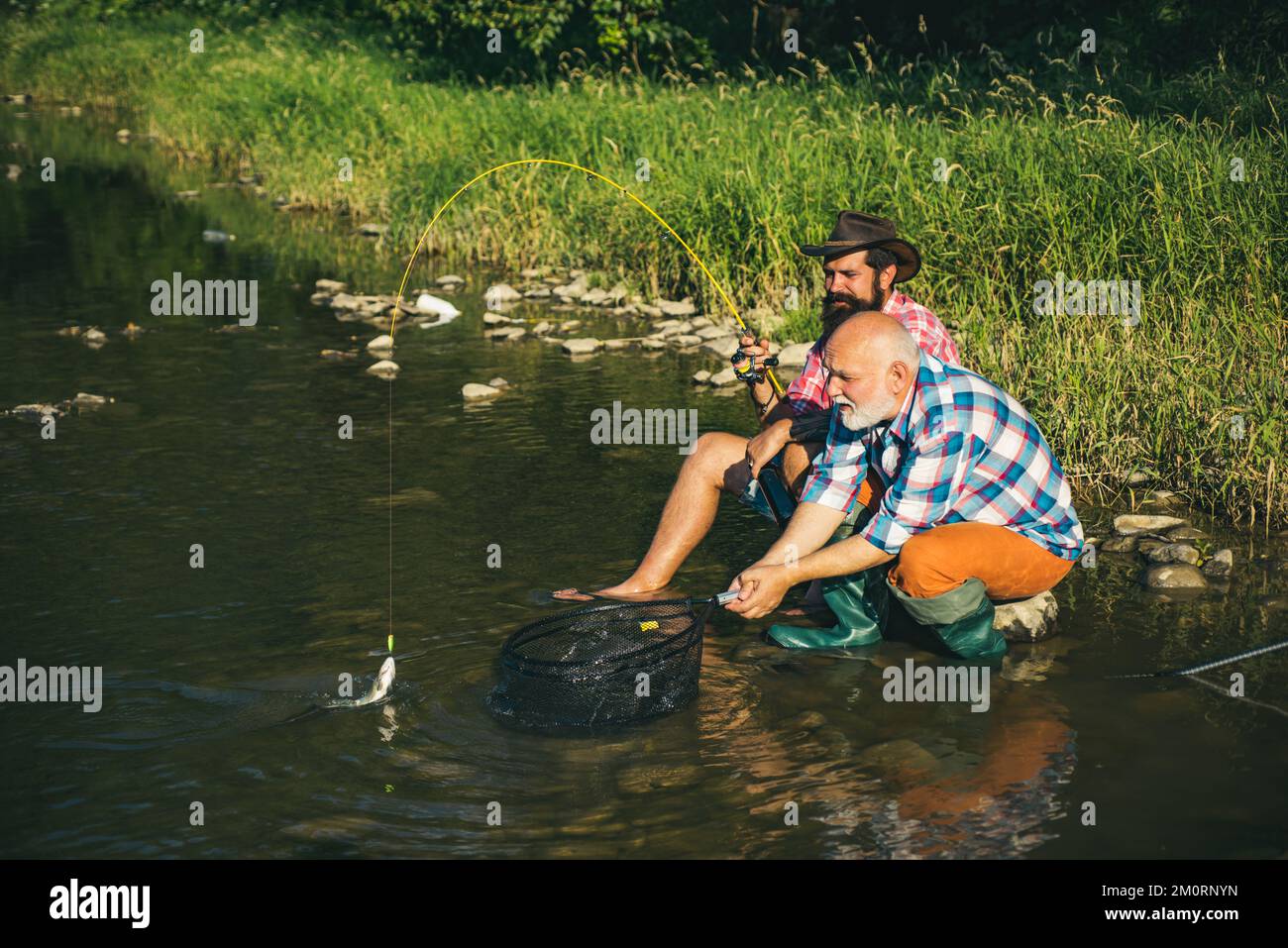 Two men friends fisherman fishing on river. Old father and son with rod ...