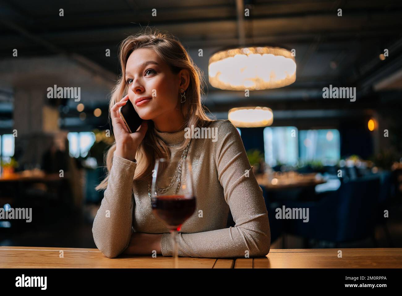 Portrait of bored pretty young woman talking on smartphone with ...