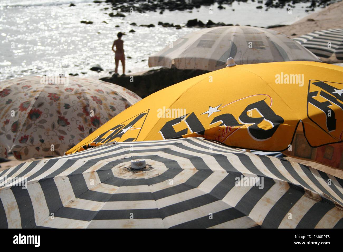 Umbrellas on the beach, N'Gor, Dakar, Senegal - silhouette of swimmer ...
