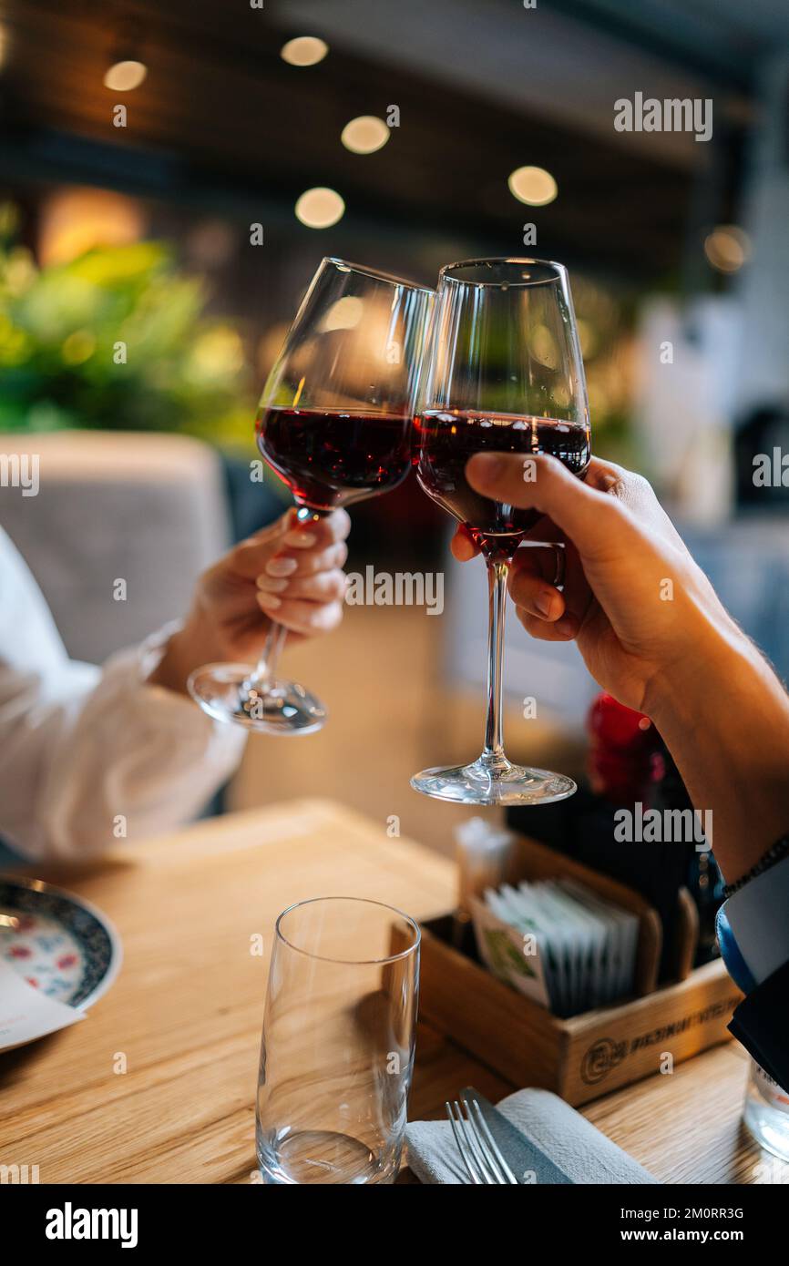 Close-up vertical shot of loving man and woman clinking glasses with ...
