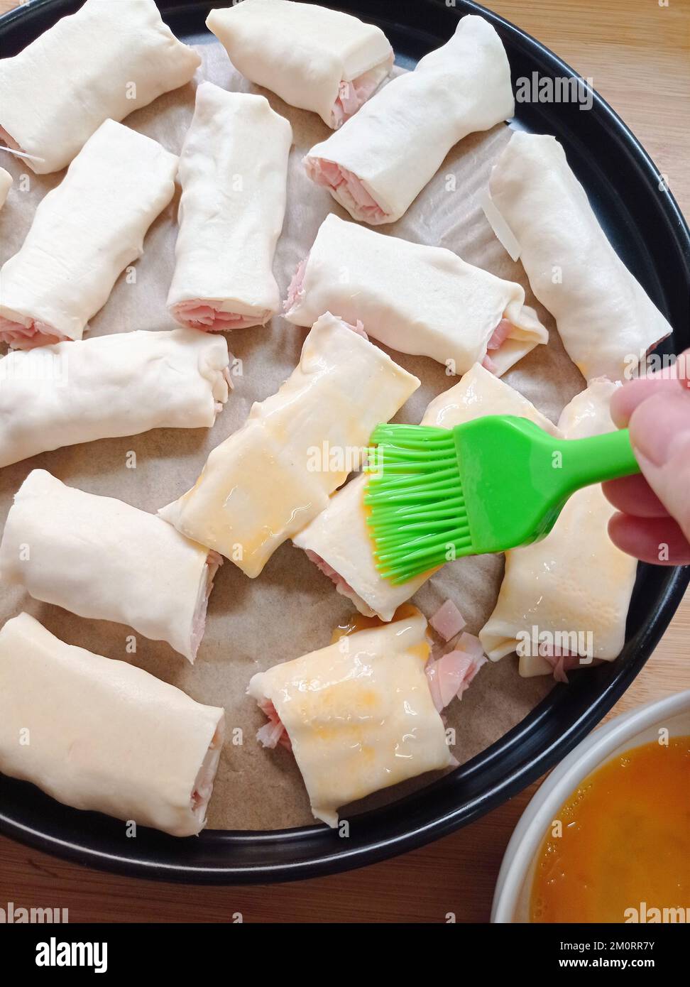 Close-Up of a person brushing egg on homemade puff pastry snacks filled ...
