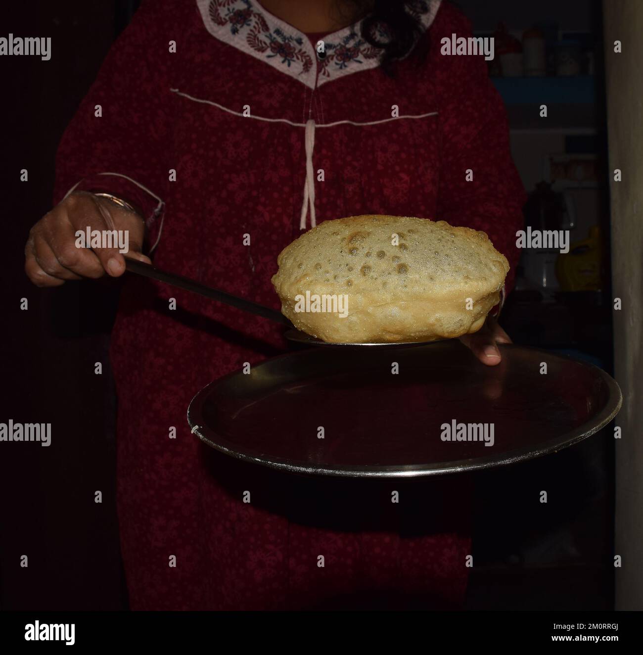 Hand of a lady showing Bhatura which is a kind of fried bread Stock ...