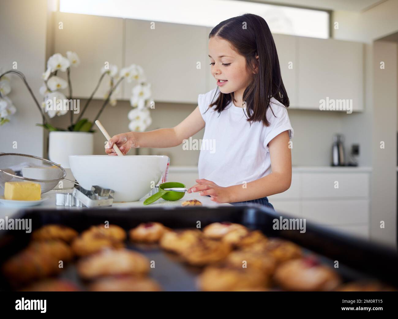 Happy little girl baking at home. Smart girl mixing batter in bowl in ...