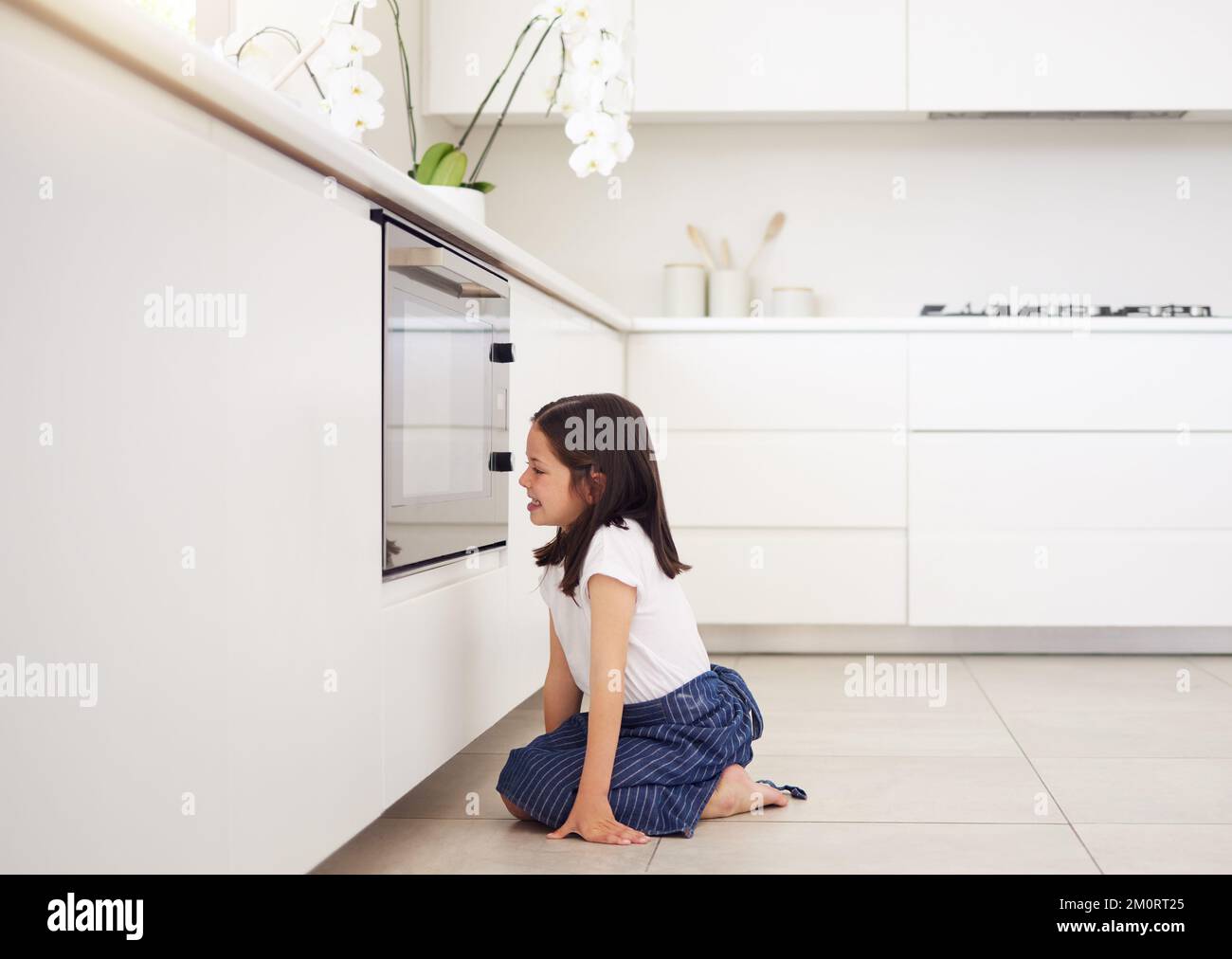 Little girl waiting by the oven for cake to bake. Autistic child ...