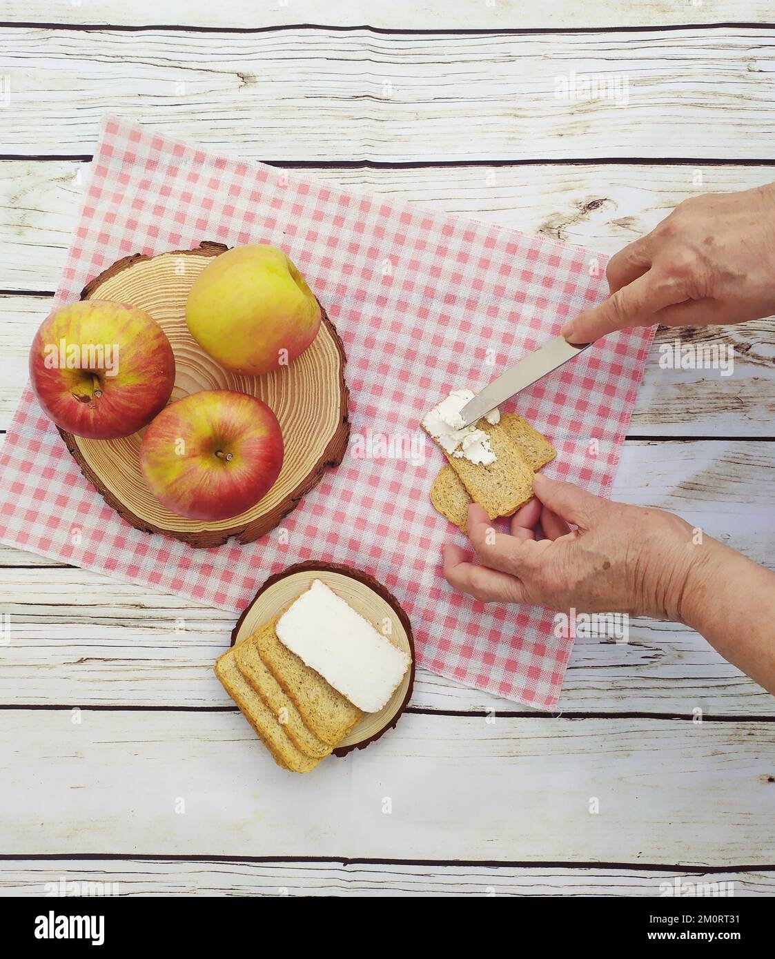 Overhead view of a person spreading cream cheese on a cracker with ...