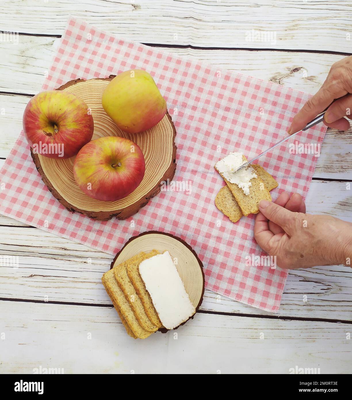 Overhead view of a person spreading cream cheese on a cracker with ...