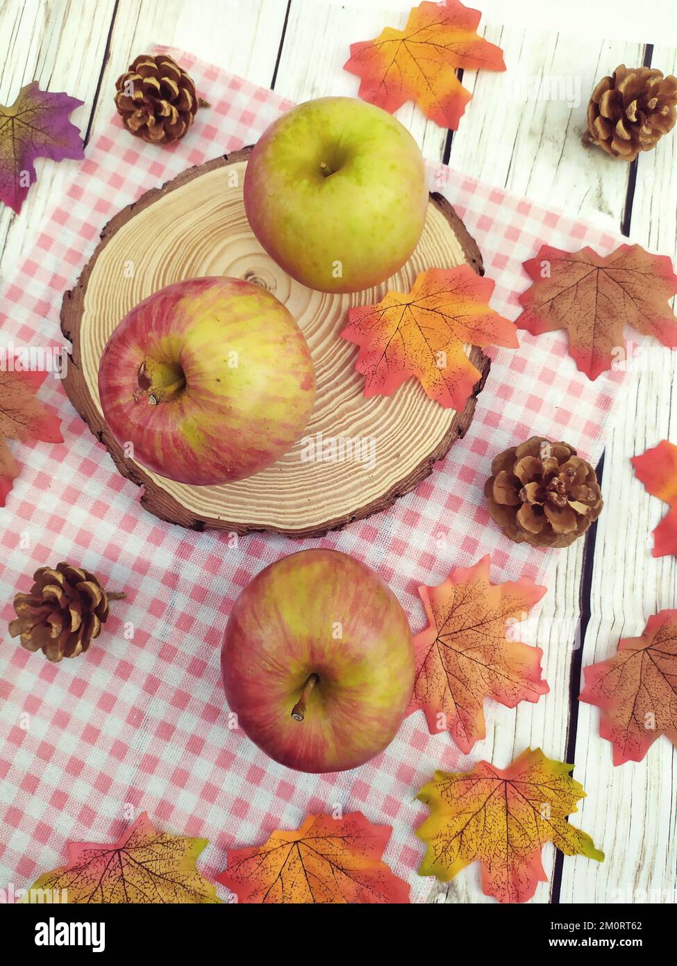 Fresh apples with rustic autumn leaves and pinecone decorations on a ...