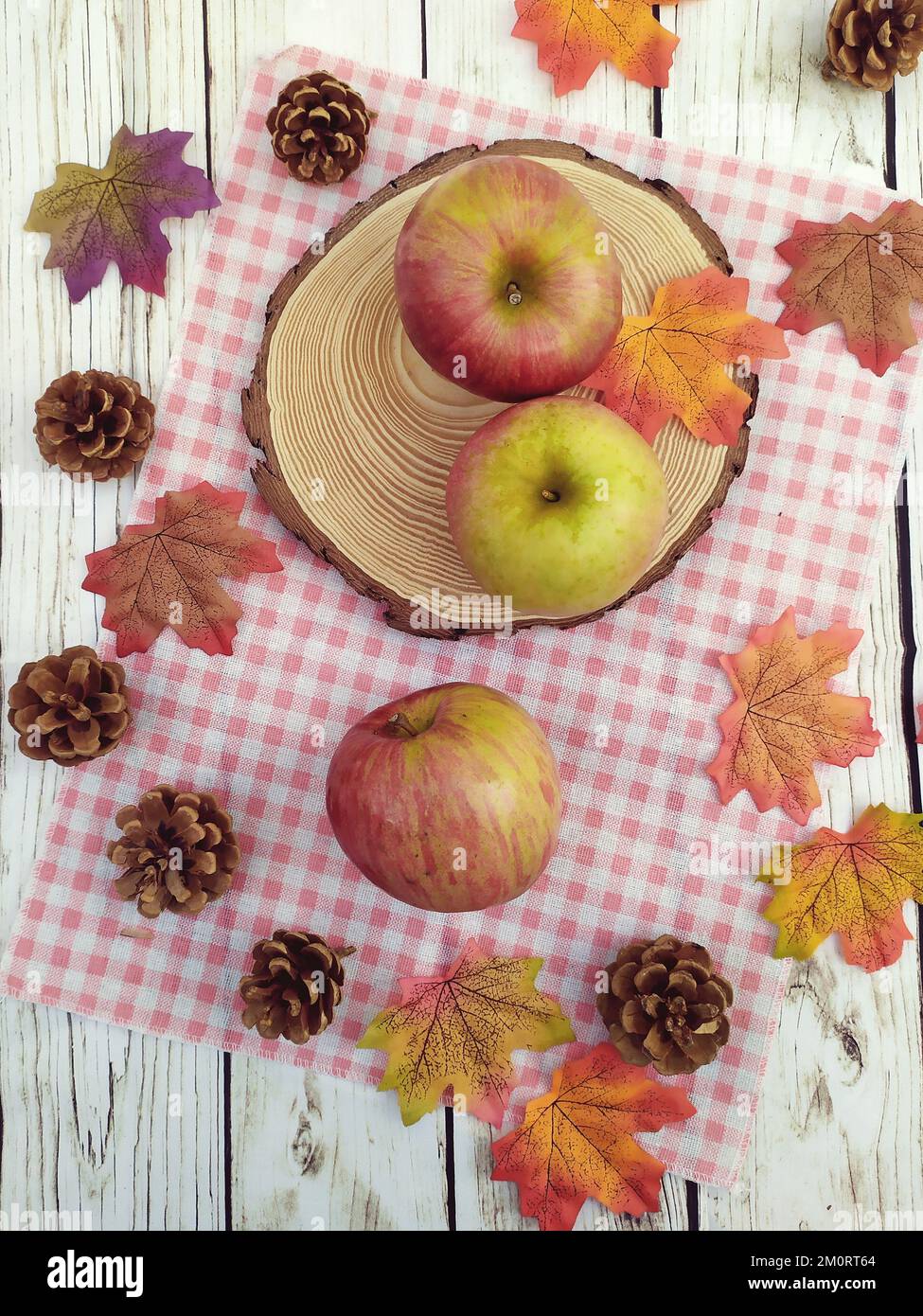 Fresh apples with rustic autumn leaves and pinecone decorations on a ...