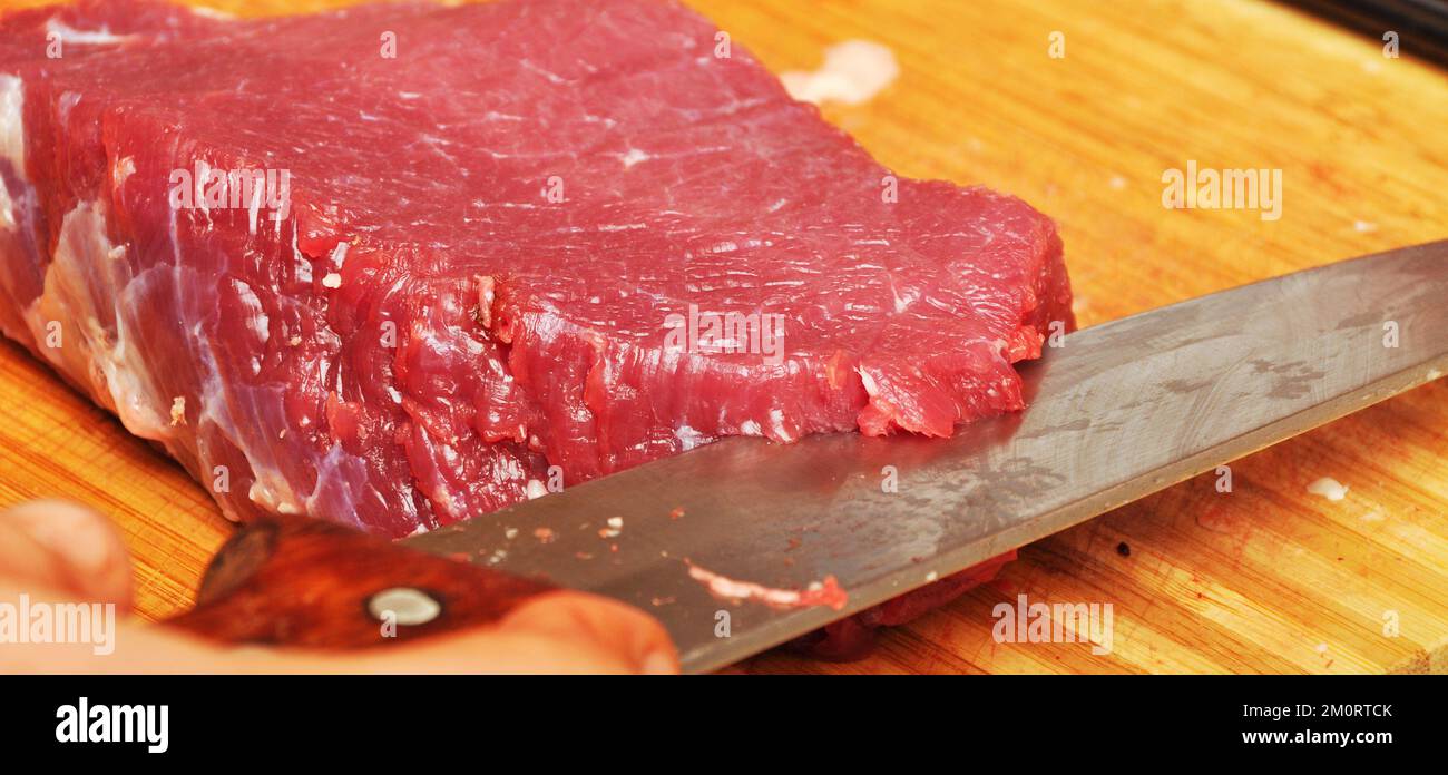 Clean very fresh red raw cow meat and a sharp knife, on cutting board ...