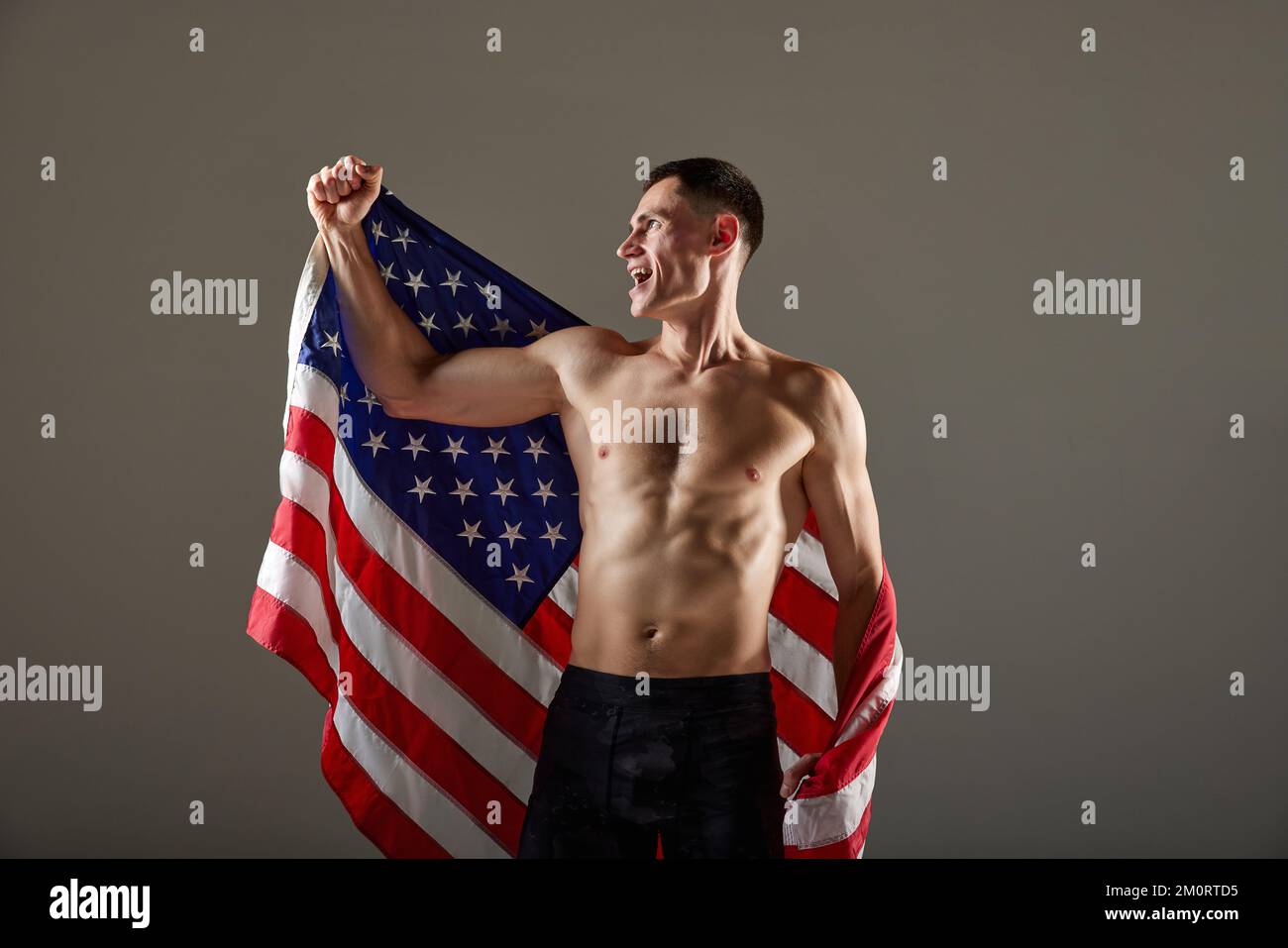 Portrait of young sportsman standing with USA flag on his shoulders and ...