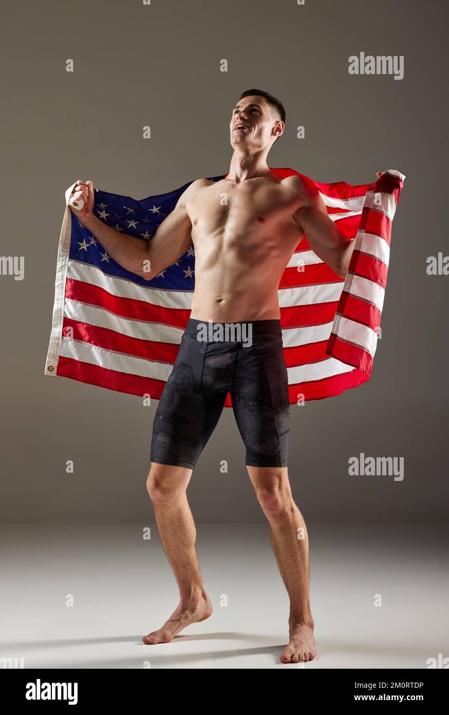 Portrait of young sportsman standing with USA flag on his shoulders and ...
