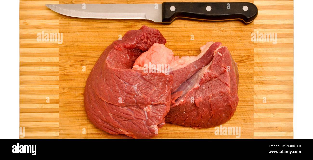 Clean very fresh red raw cow meat and a sharp knife, on cutting board ...