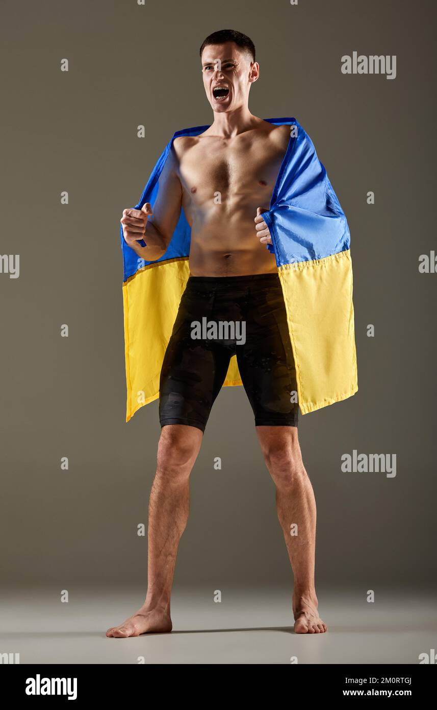 Portrait of young sportsman standing with Ukraine flag on his shoulders ...