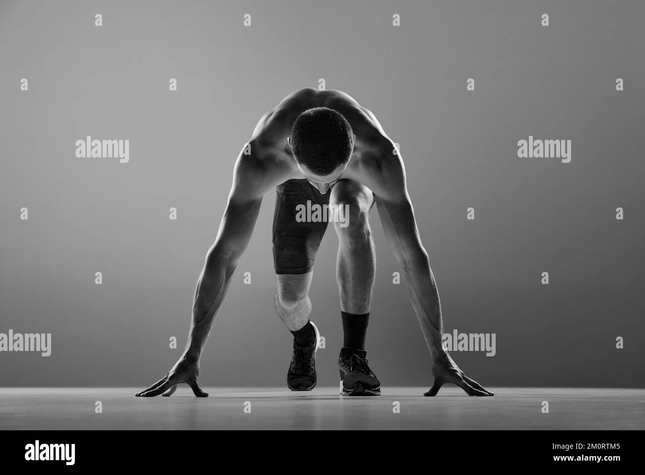 Strength and energy. Muscular athlete, runner at start line isolated ...