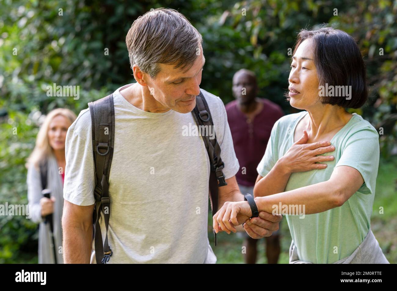 Diverse middle-aged couple taking a walk in the woods and checking lady ...
