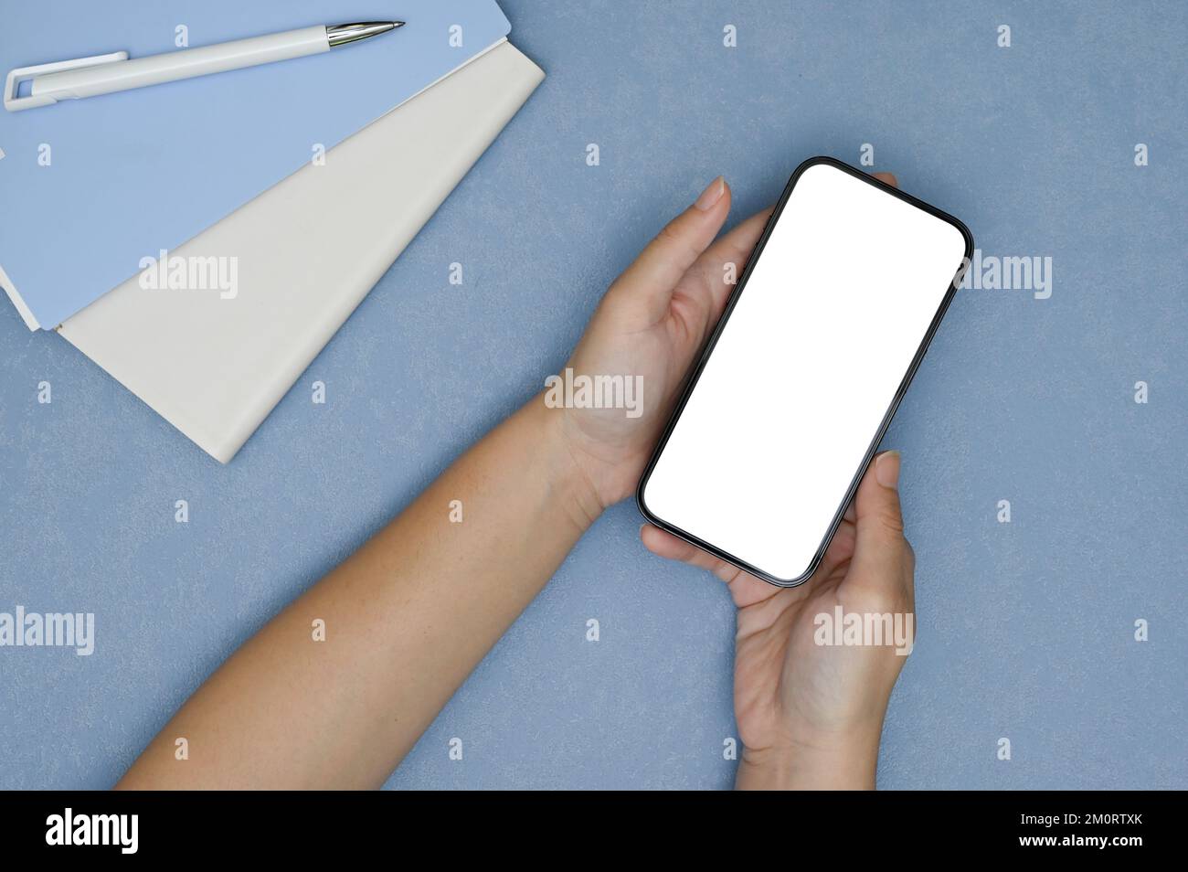 Top view, A female hands holding a smartphone white screen mockup over ...