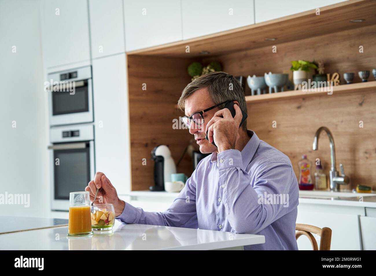 Middle-aged professional man having breakfast on kitchen counter at ...