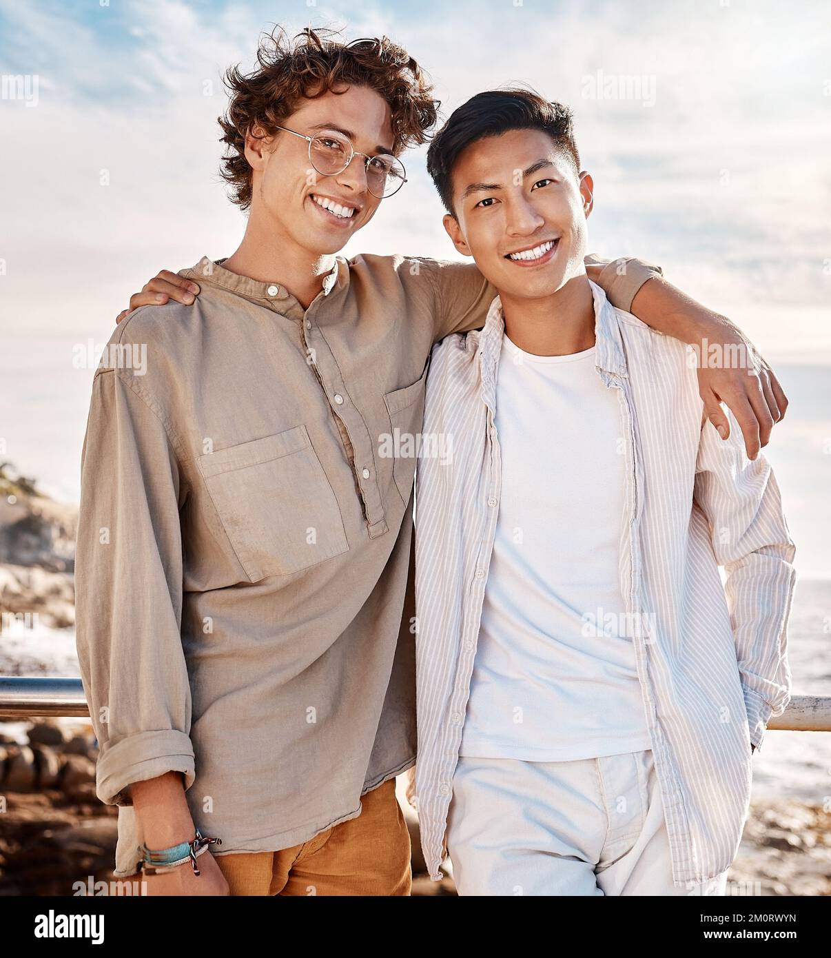 Portrait of two attractive young men standing together on the beach ...