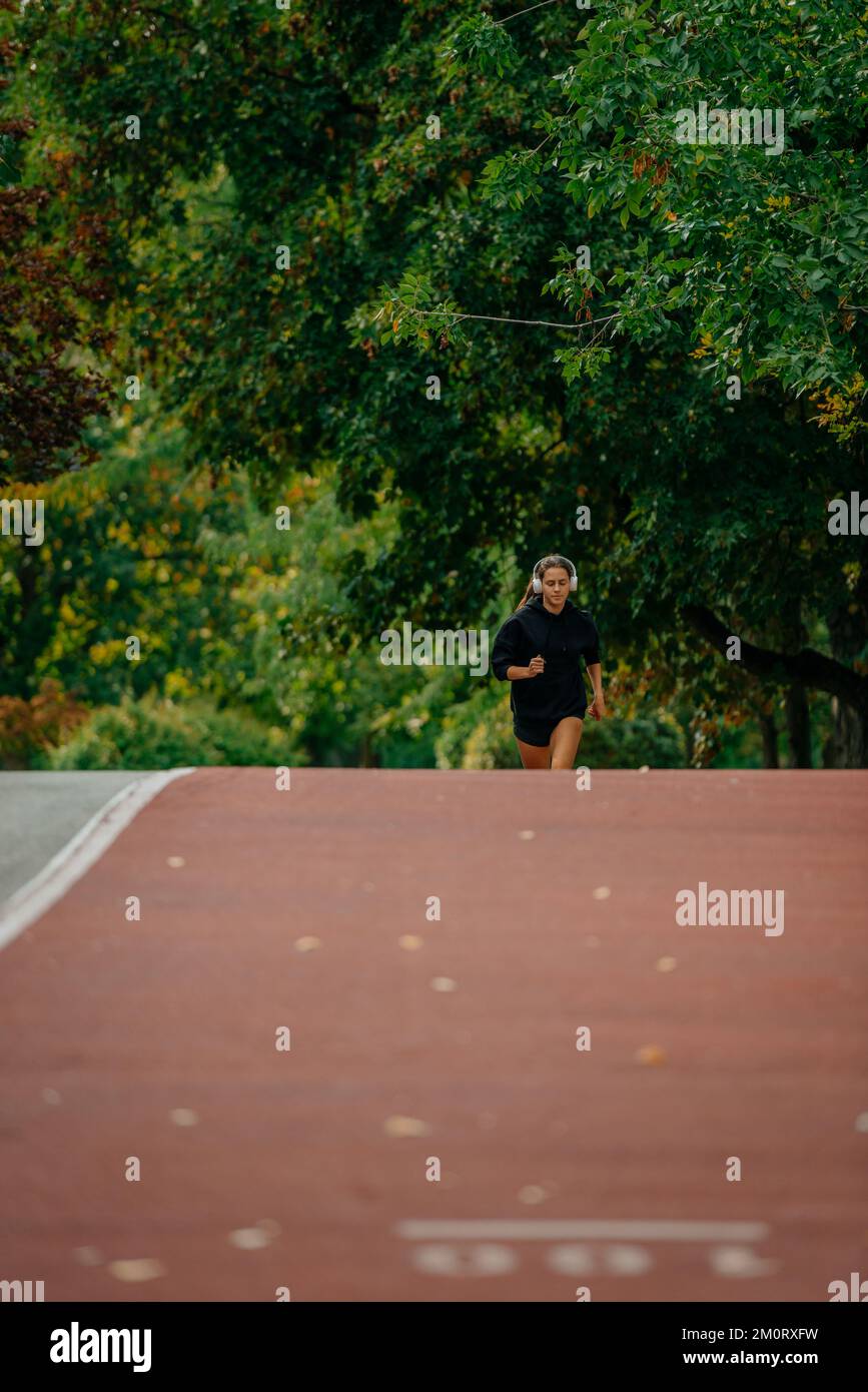 Woman running on a sports track in nature Stock Photo - Alamy