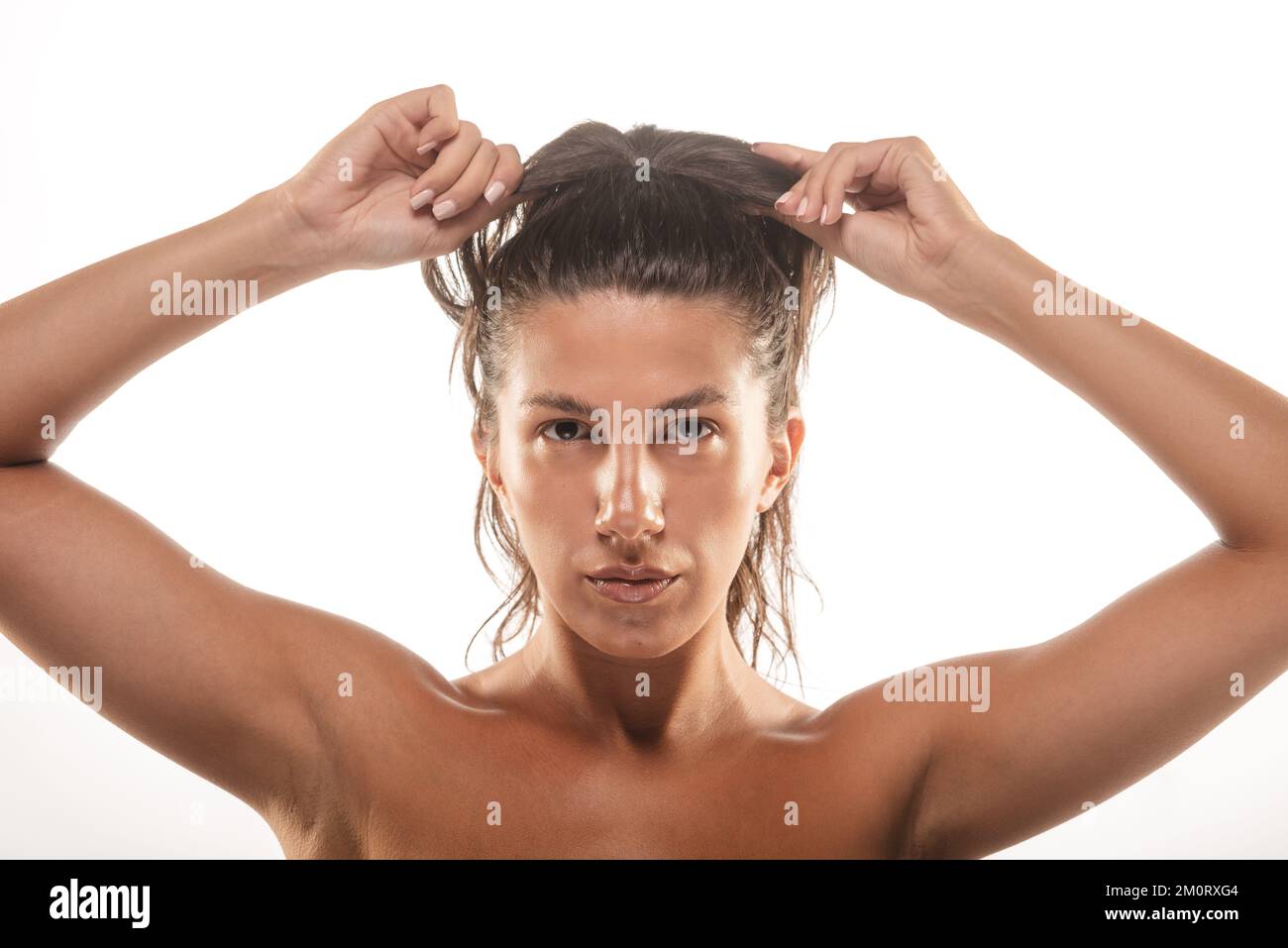 Beautiful brunette girl fixing her ponytail at the studio on a white ...