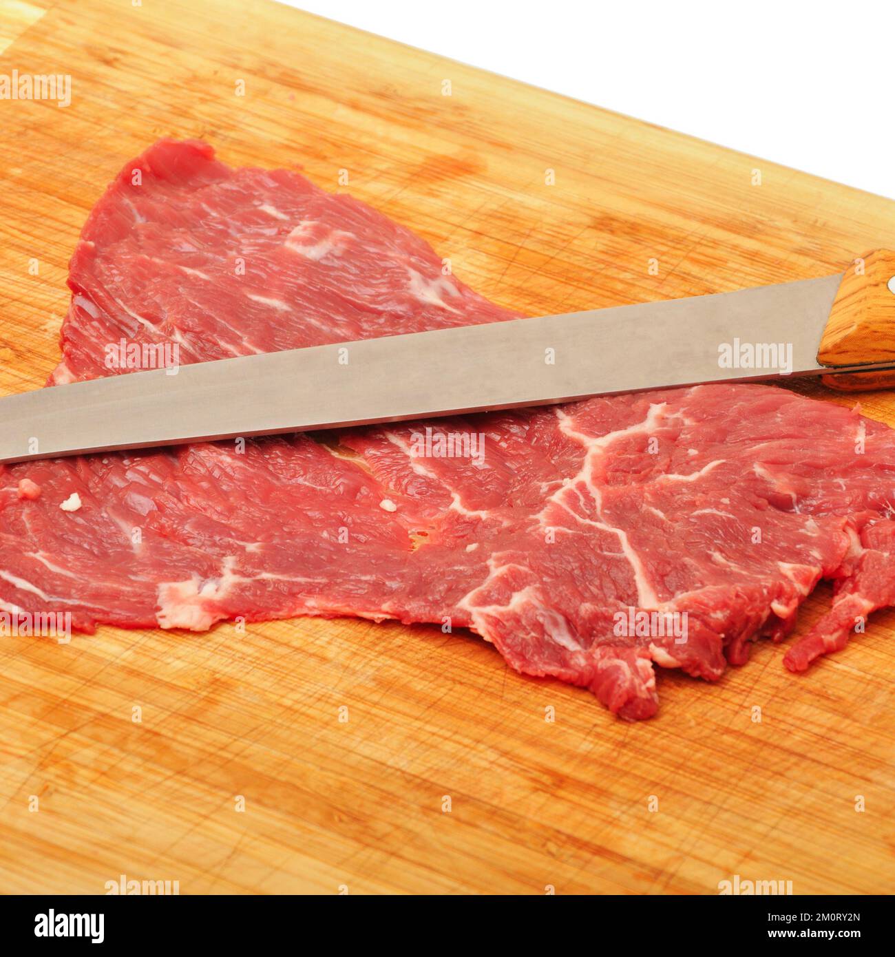 Clean very fresh red raw cow meat and a sharp knife, on cutting board ...