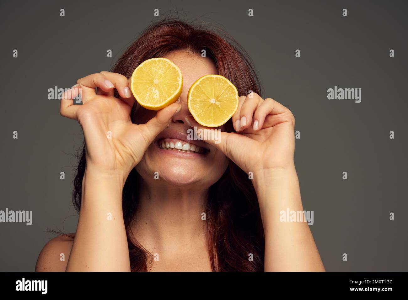 Portrait of beautiful red-haired woman, smiling, posing with lemons ...