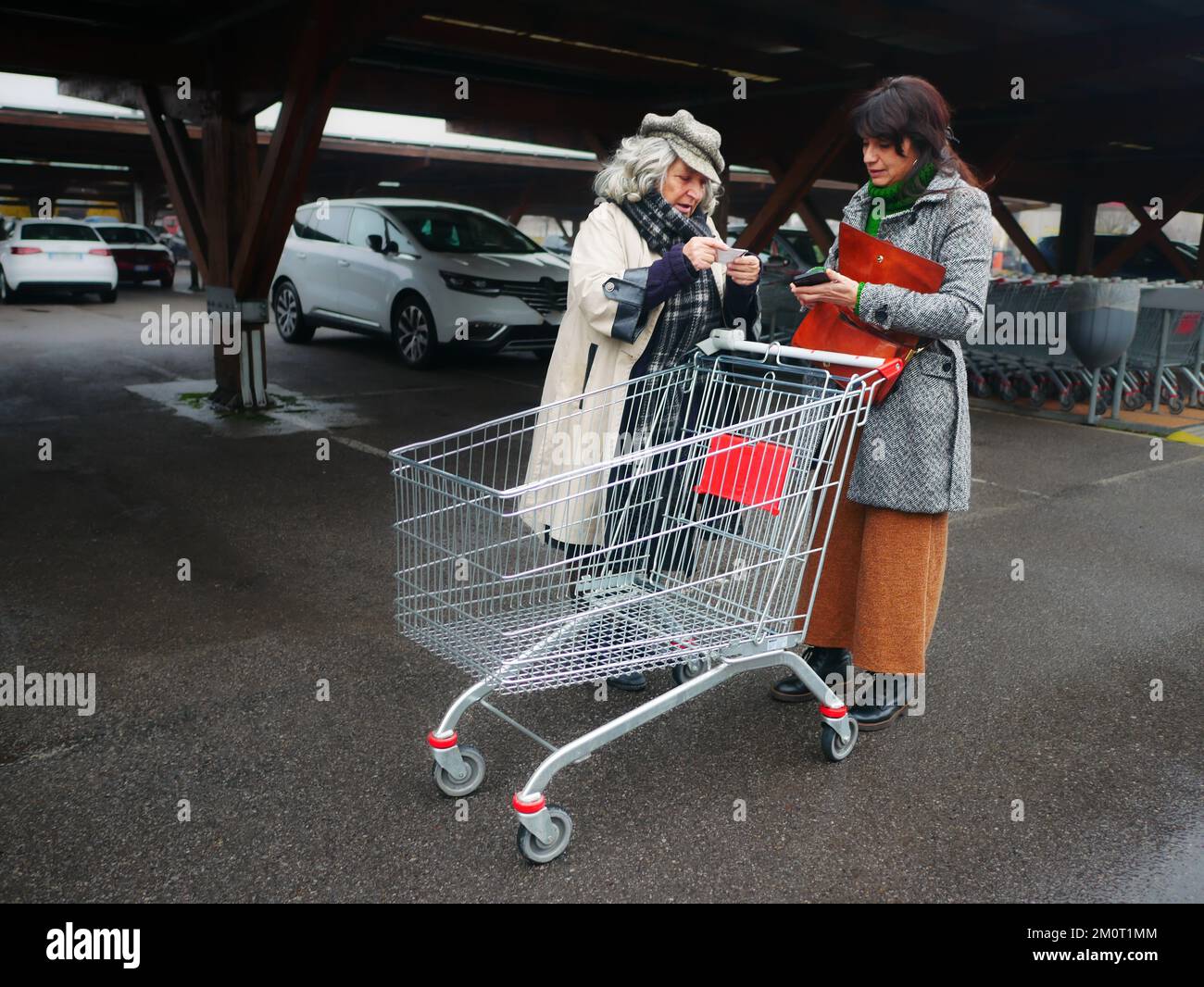 senior european lady and hispanic young adult woman pushing cart ...