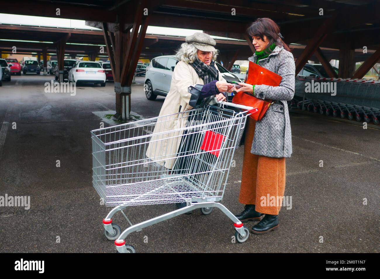 senior european lady and hispanic young adult woman pushing cart ...