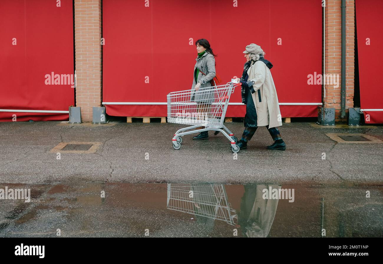 senior european lady and hispanic young adult woman pushing cart ...