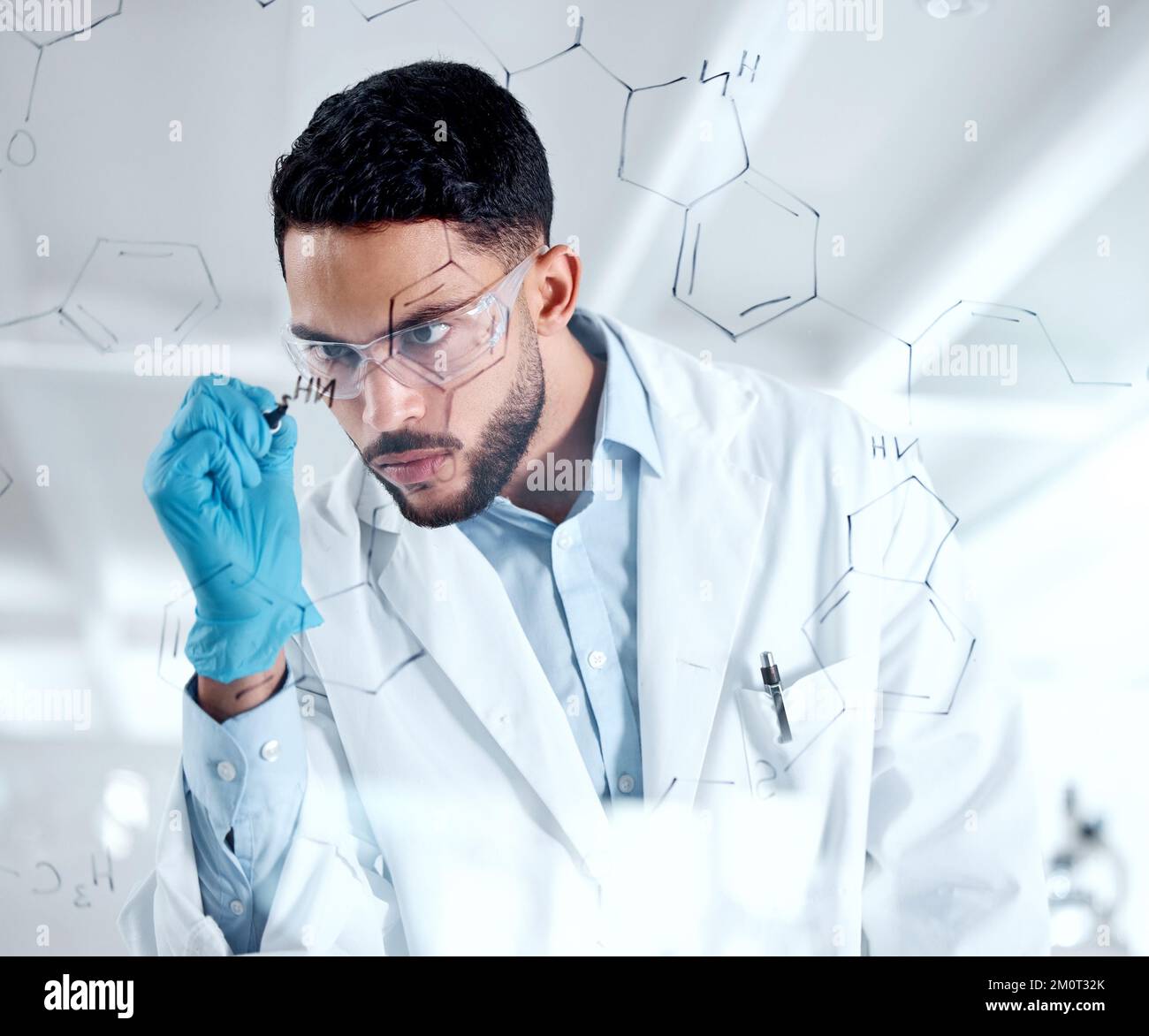 Young focused hispanic chemist drawing a dna structure on a board while ...