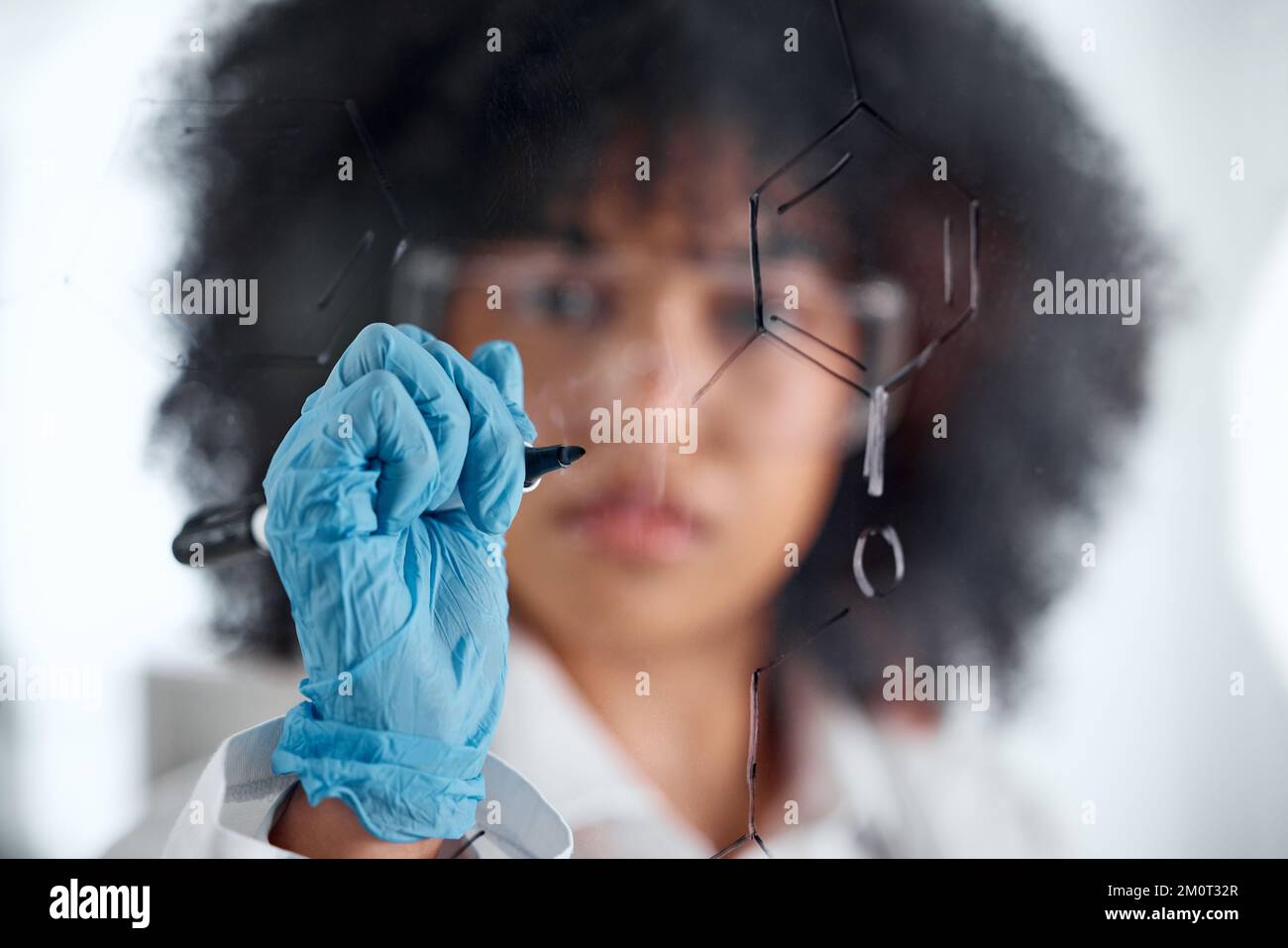 Closeup of the hand of a young mixed female scientist writing and ...