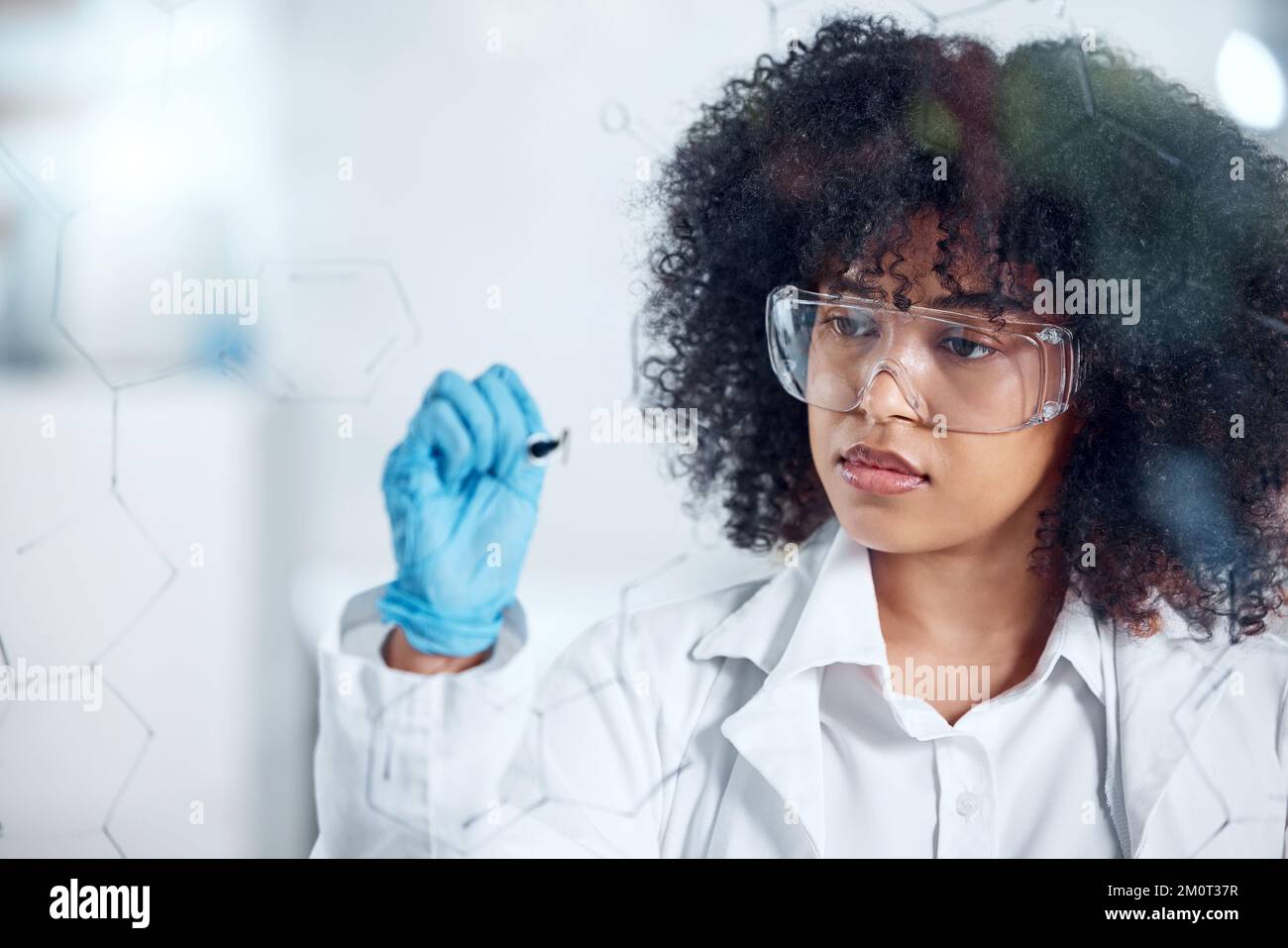 One serious young mixed race female scientist with a curly afro writing ...