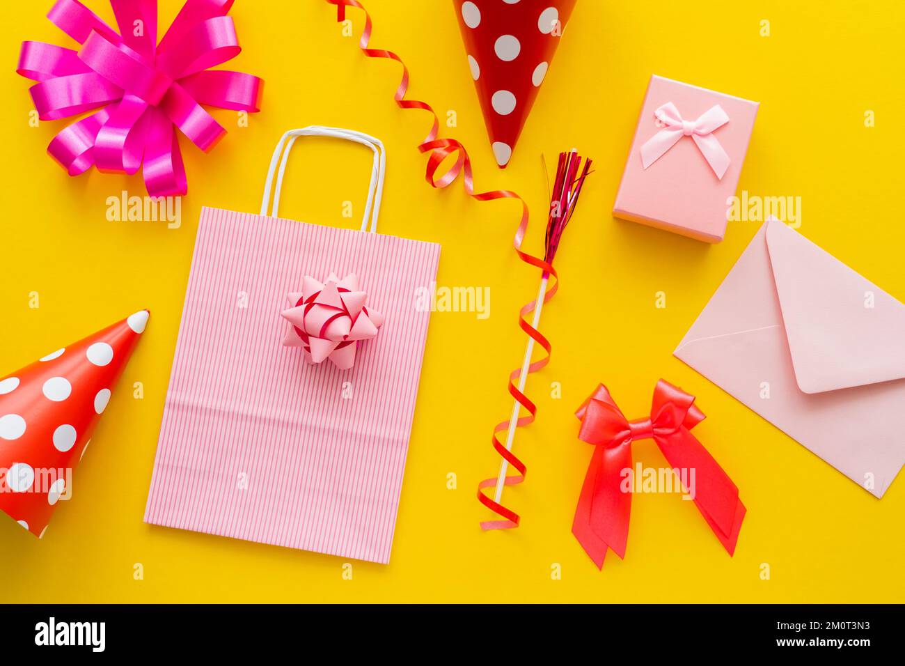 Top view of gift box near party caps and shopping bag on yellow ...