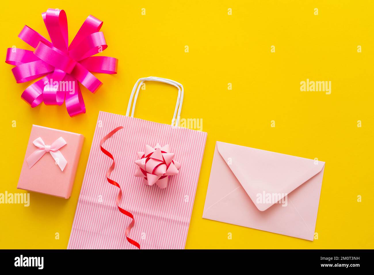 Top view of shopping bag near gift box and envelope on yellow ...