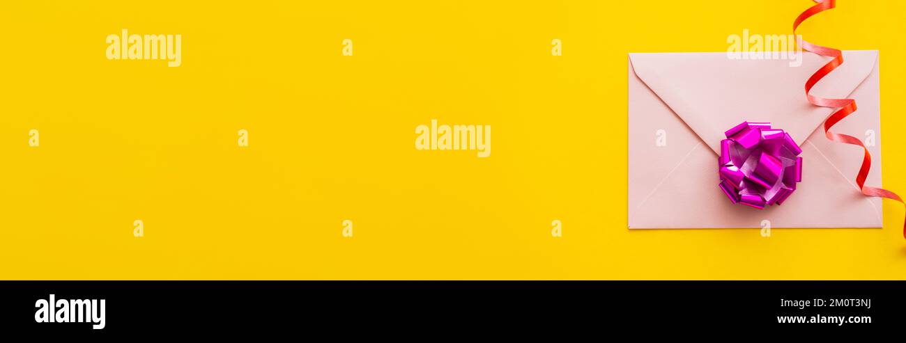 Top view of serpentine on envelope with gift bow on yellow background ...