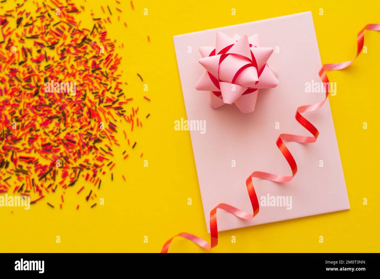 Top view of pink greeting card with gift bow and blurred sprinkles on ...
