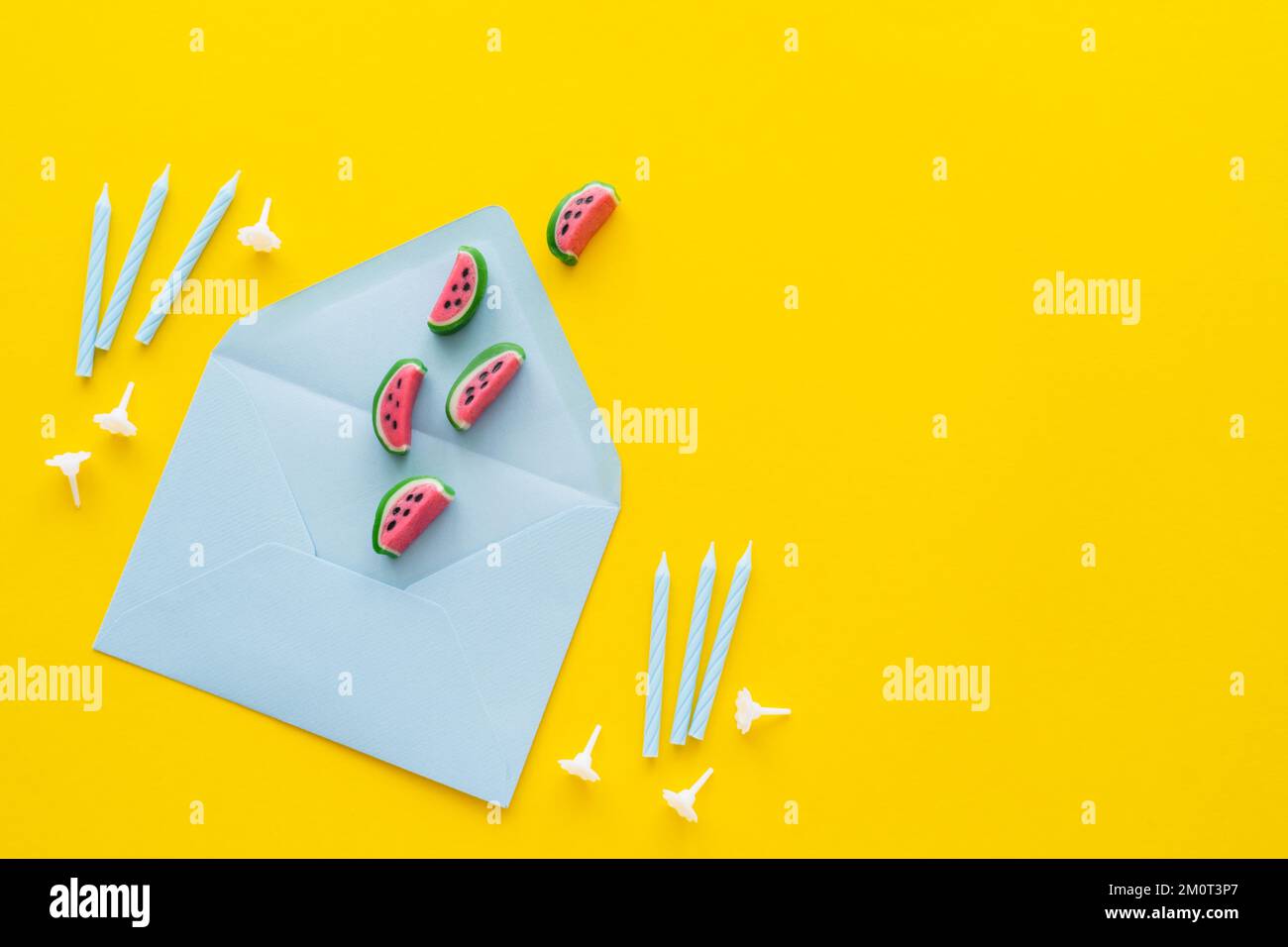 Top view of candies on envelope near festive candles on yellow ...
