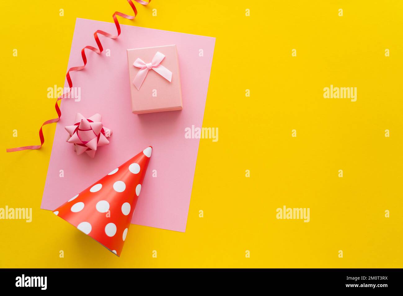 Top view of gift box on greeting card near party cap and serpentine on ...