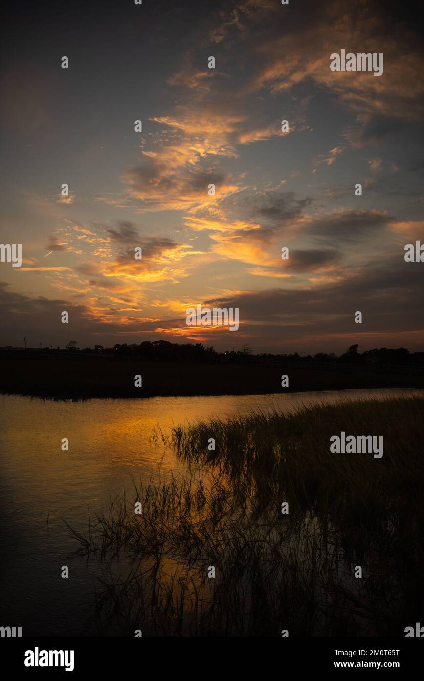 A vertical shot of a beautiful sunset on Shem creek with a cloudy sky ...