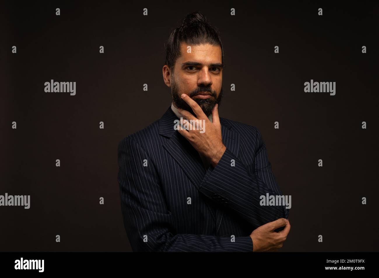 A beautiful shot of a Hispanic man showing emotions in front of a black ...