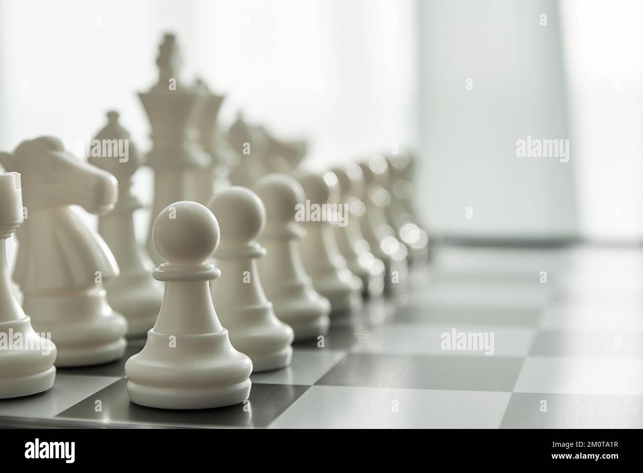 White Chess figures in a row on the board with blurred perspective view ...