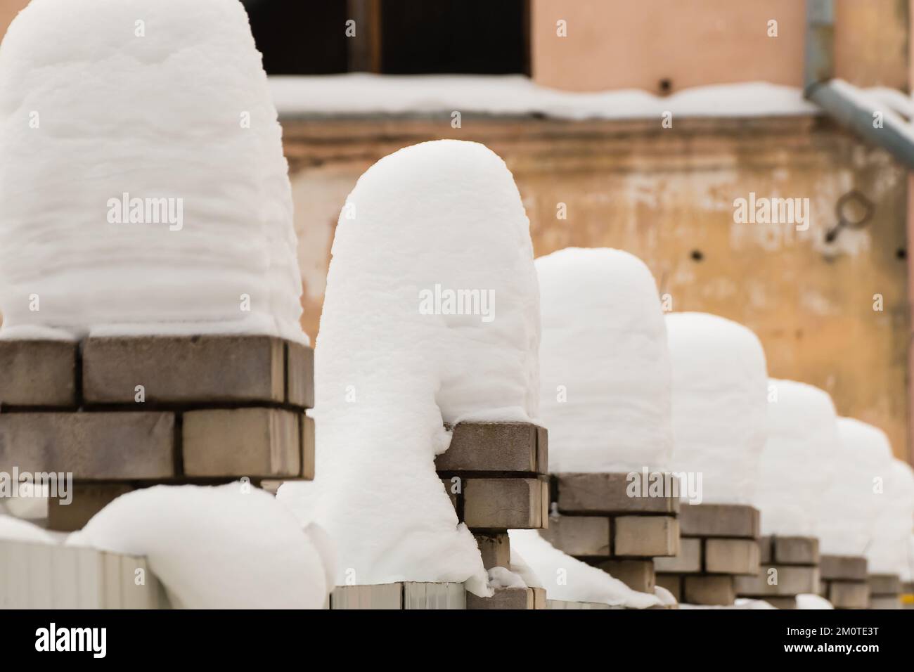 High, even, columns of snow on the brick pillars of the fence. An even ...
