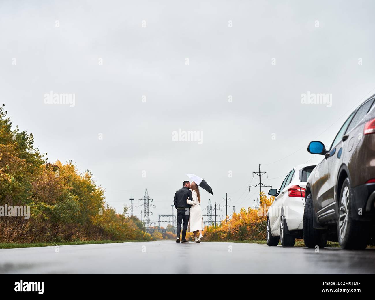 Young couple in love kissing under umbrella, walking on the road near ...