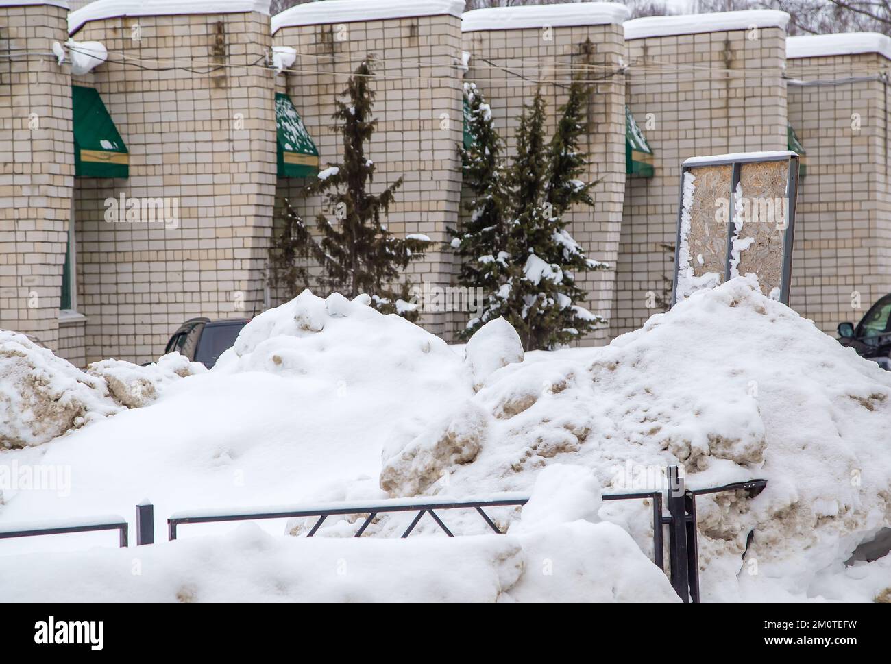 A large snowdrift against the background of a wall of a brick building ...