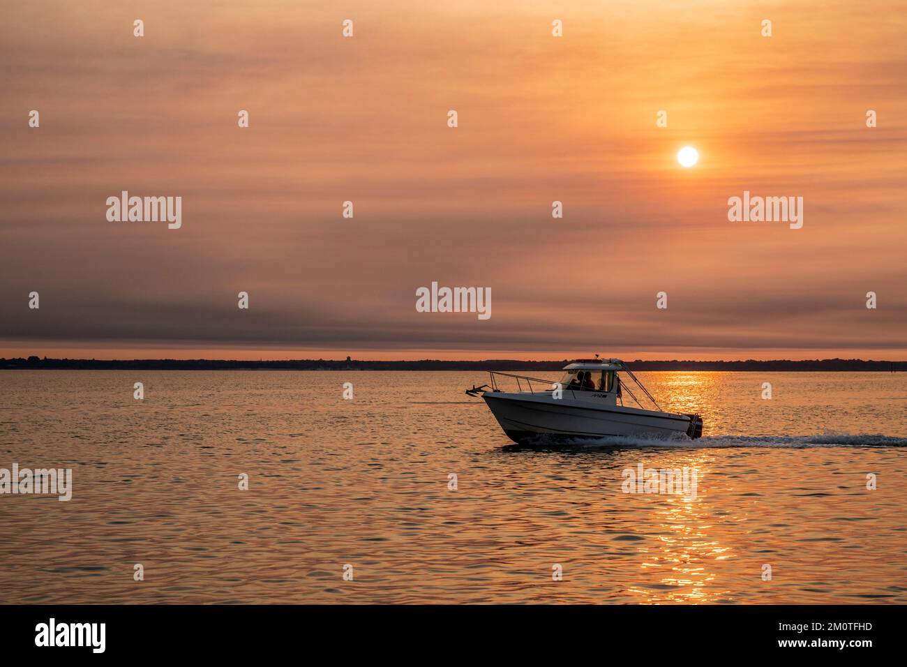 France, Gironde, Arcachon, a motor boat sails on the basin at sunrise ...